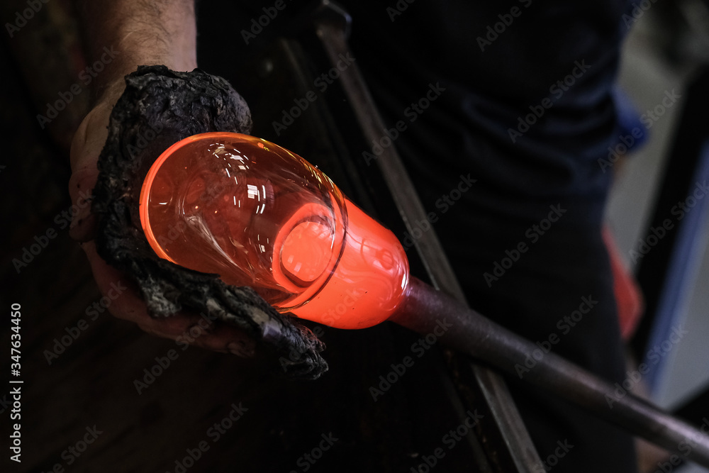 Artist glass blower working glass paste on his workbench. A glass ...