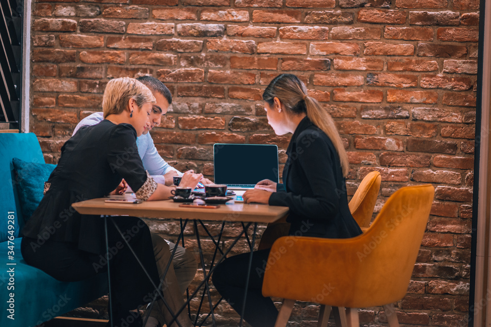Group of three people with their laptop and tablet working on a project ...