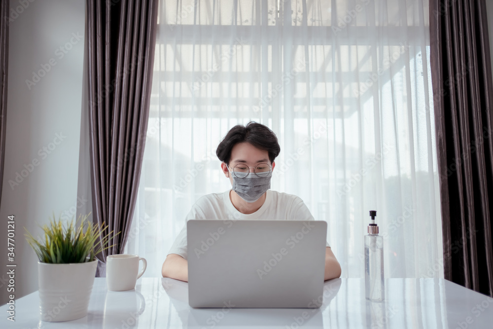 Asian man wearing mask working from home with laptop computer self ...