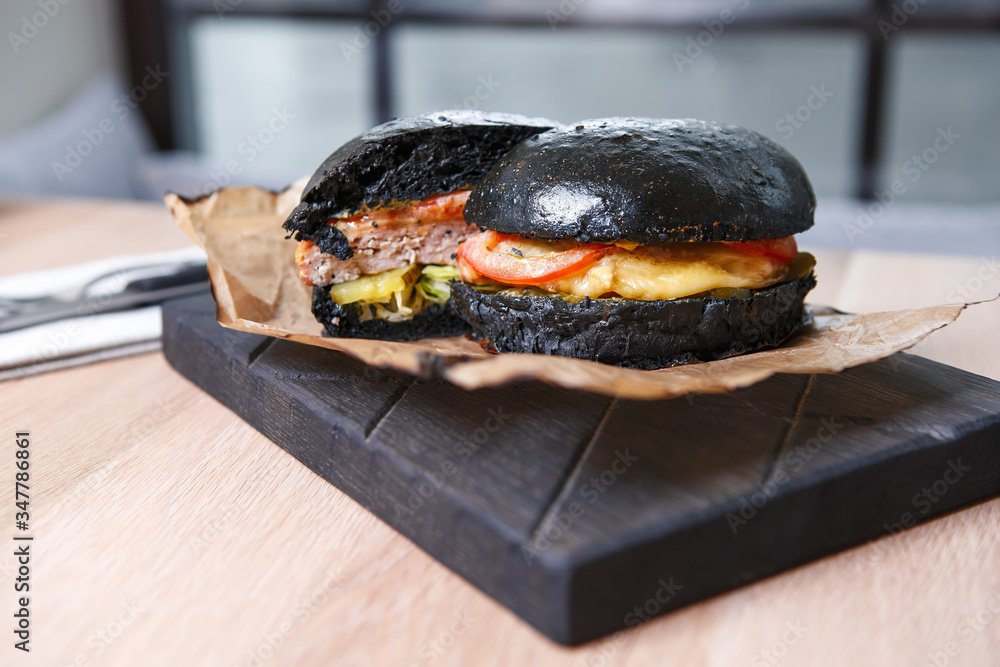 Black cheeseburger on wooden plate in restaurant.Delicious hamburger ...