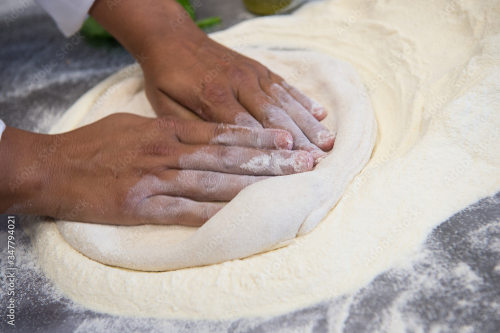 the hands of a pizza maker who works for the various stages of ...