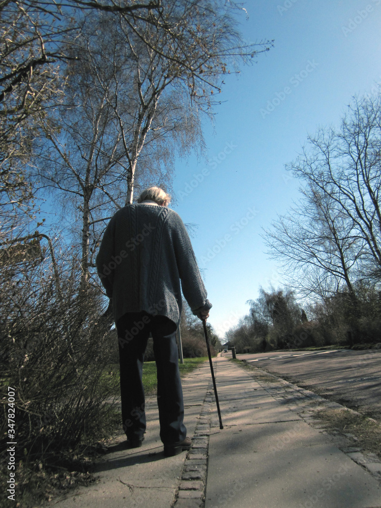 Tubby old man with bent back and walking stick in the countryside with ...
