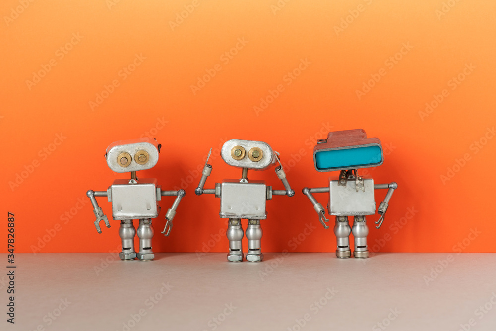 Three metal silver robots on peach colour background. Simplified ...