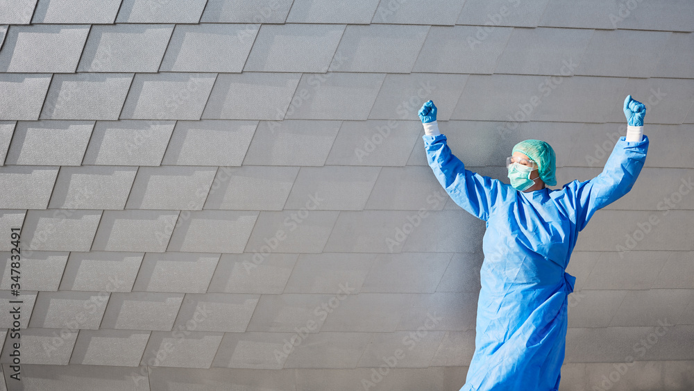 Doctor cheers with clenched fists in front of clinic in protective ...