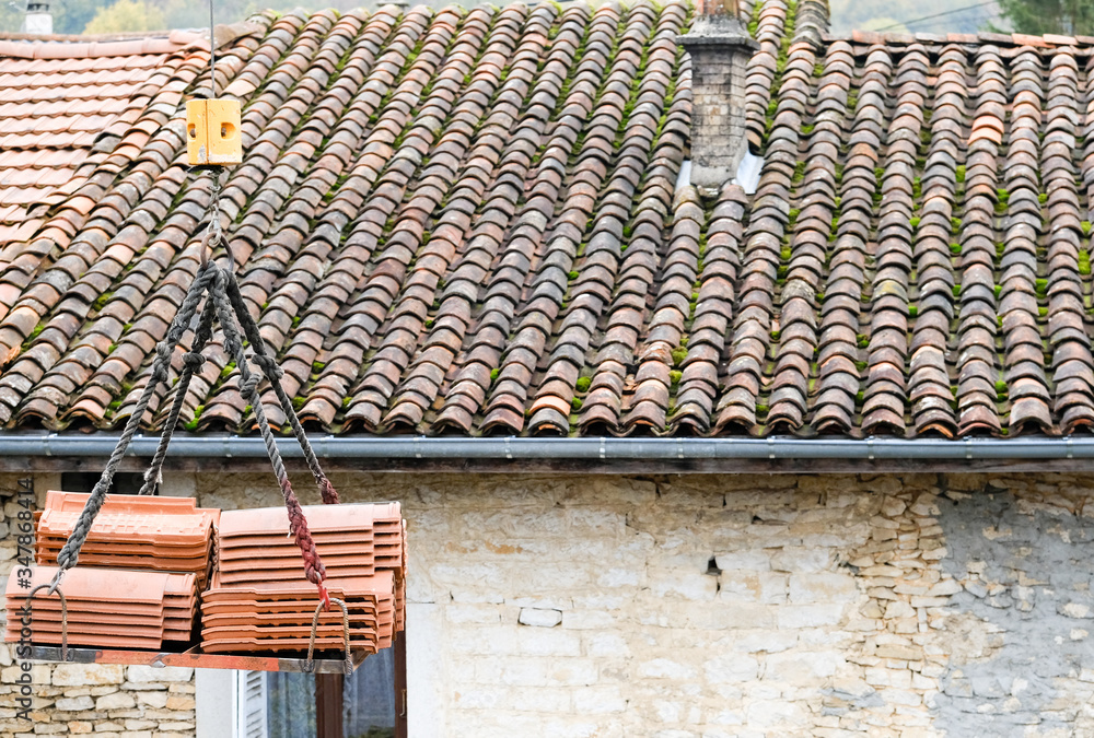 construction worker on a renovation roof covering it with tiles using ...