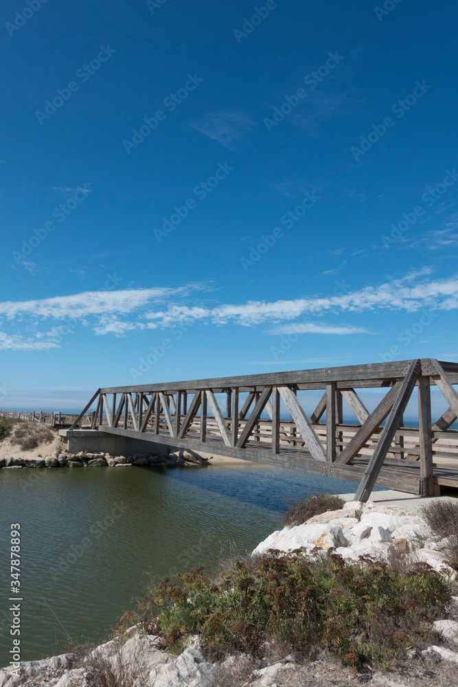 wooden bridge crossing a small river linking a path to a boardwalk ...