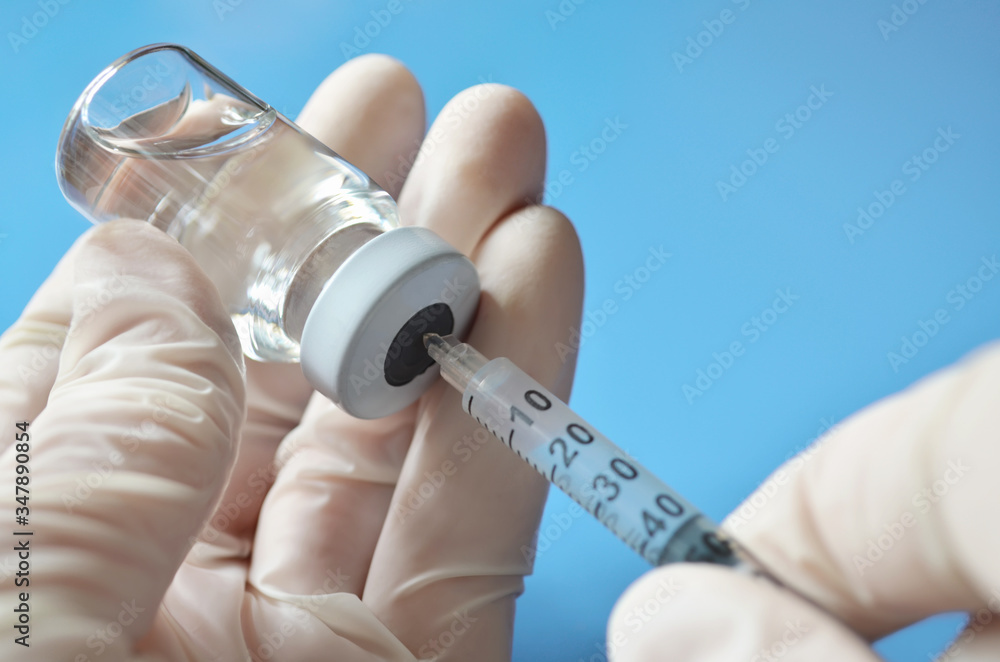 Medical professional in a rubber gloves extract a drug dose from a ...