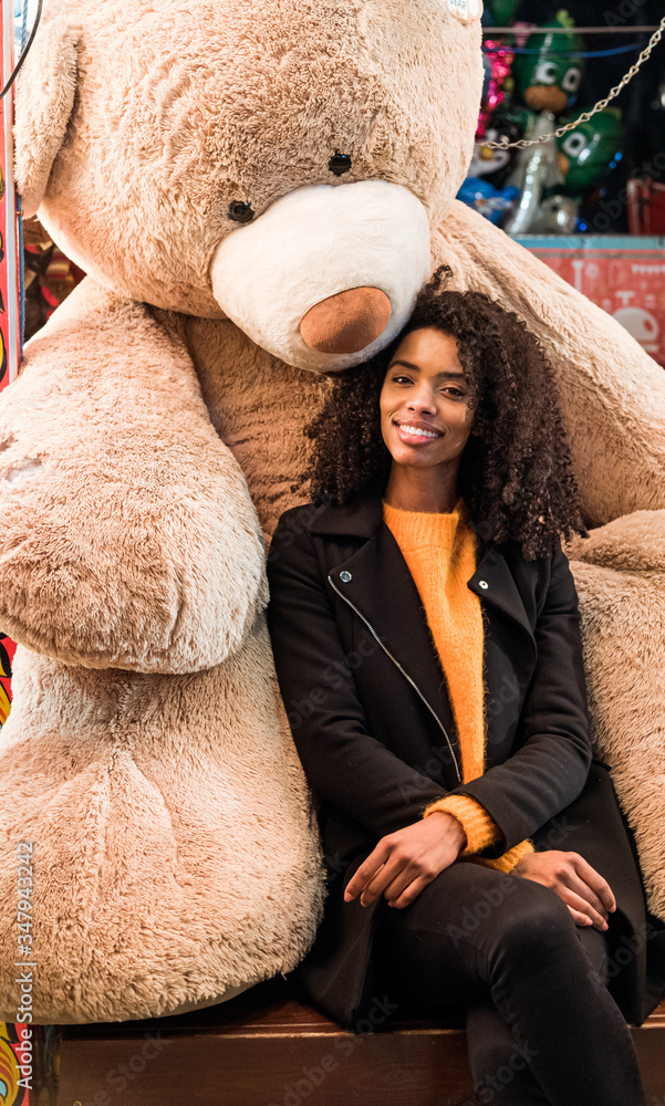 Happy ethnic woman sitting with giant teddy bear Stock Photo | Adobe Stock
