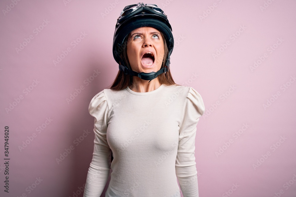 Young beautiful motorcyclist woman with blue eyes wearing moto helmet ...