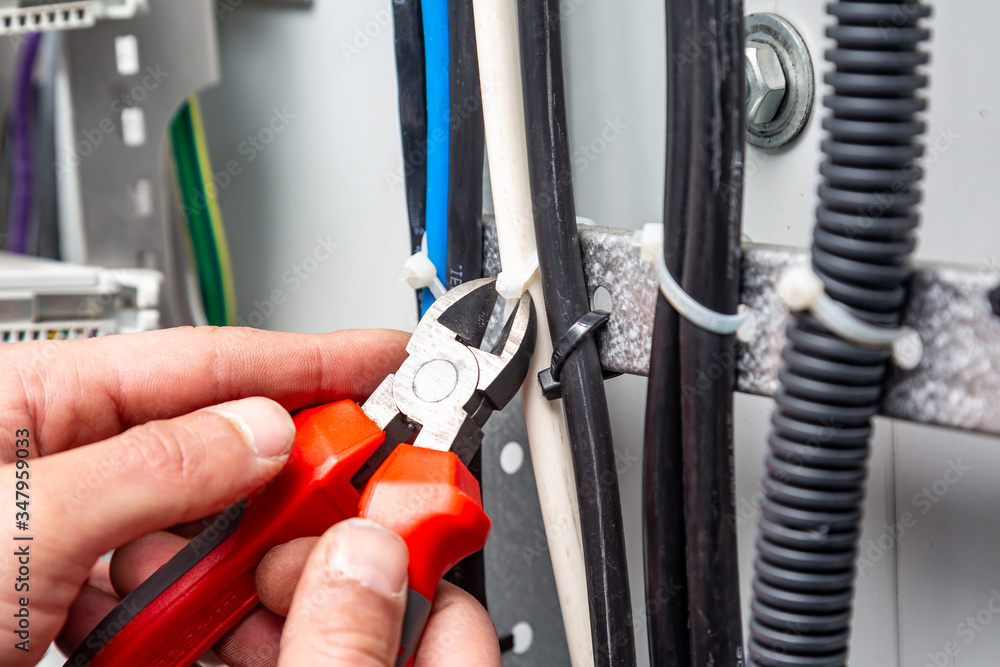 Hands with wire cutters cut the cable ties from the wires on the cable ...