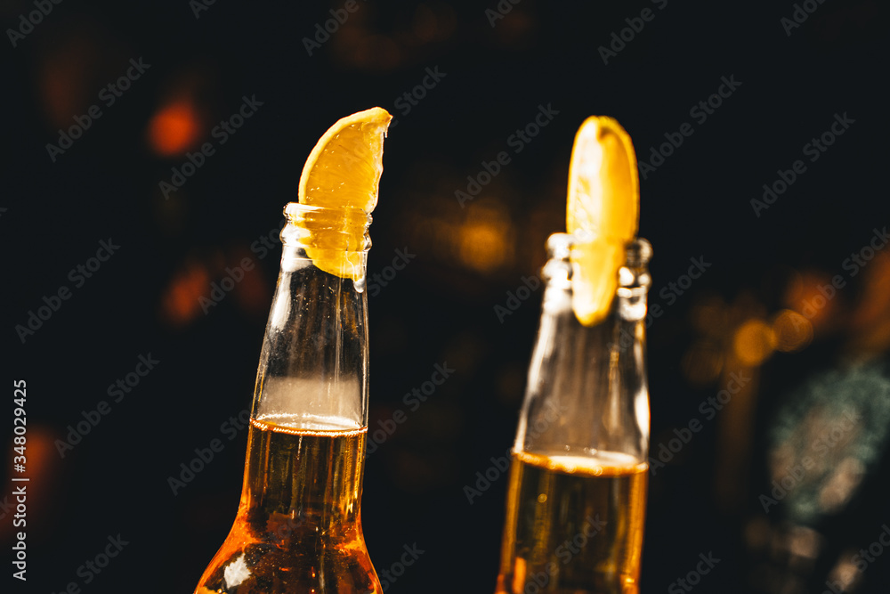 Lemon slices in bottlenecks of gold corona beer, close up with bokeh ...