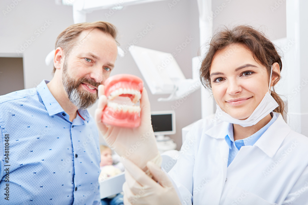 Zahnärztin mit Patient zeigt Modell von Gebiss foto de Stock | Adobe Stock