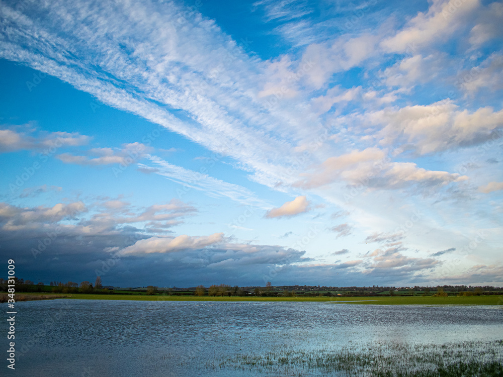 Rural landscape with dramatic cloudy sky, farm land floded by local ...