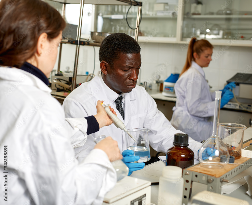 African american male lab technician writing report after chemical ...