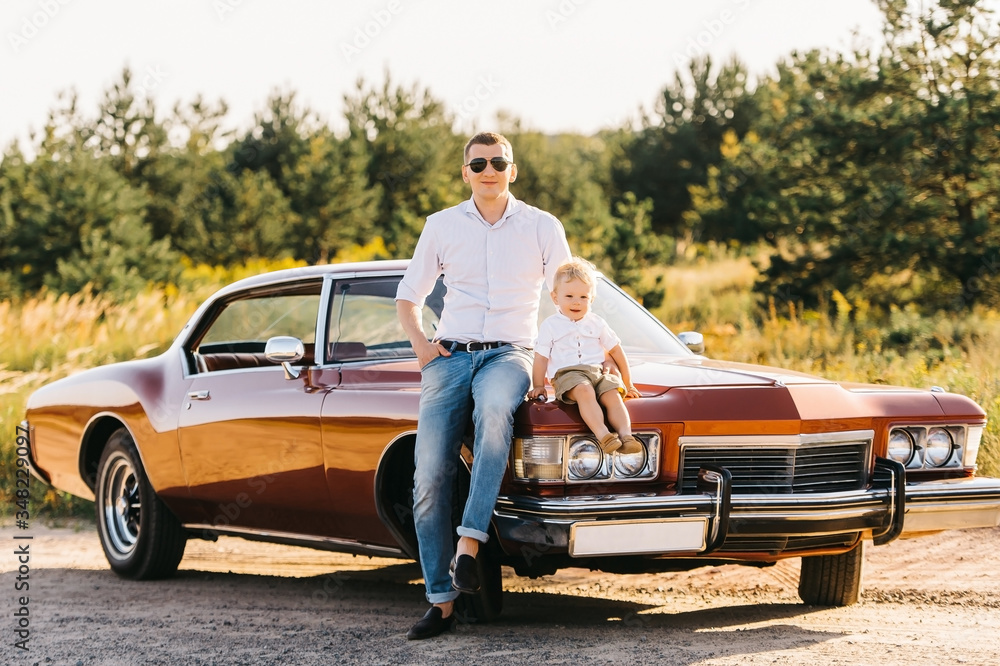 Buick Riviera in retro style. Unique car. Dad and son are sitting on ...