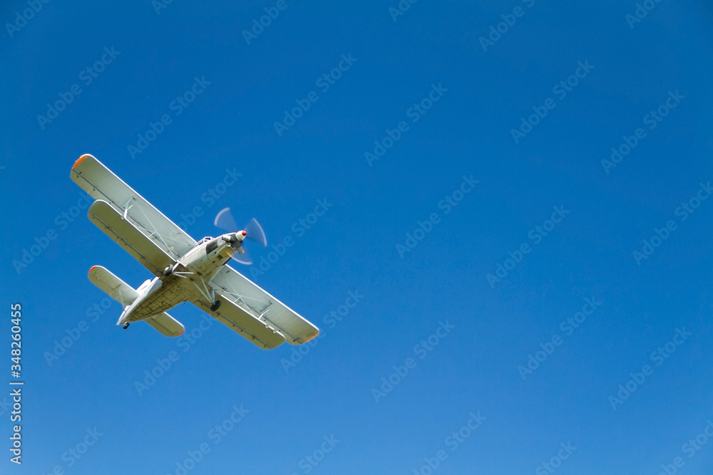 Retro airplain - biplane flying the air against a blue sky, with a fast ...