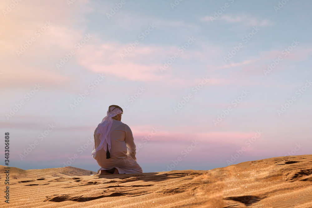 Arabic man with traditional emirates clothes sitting on kness in the ...