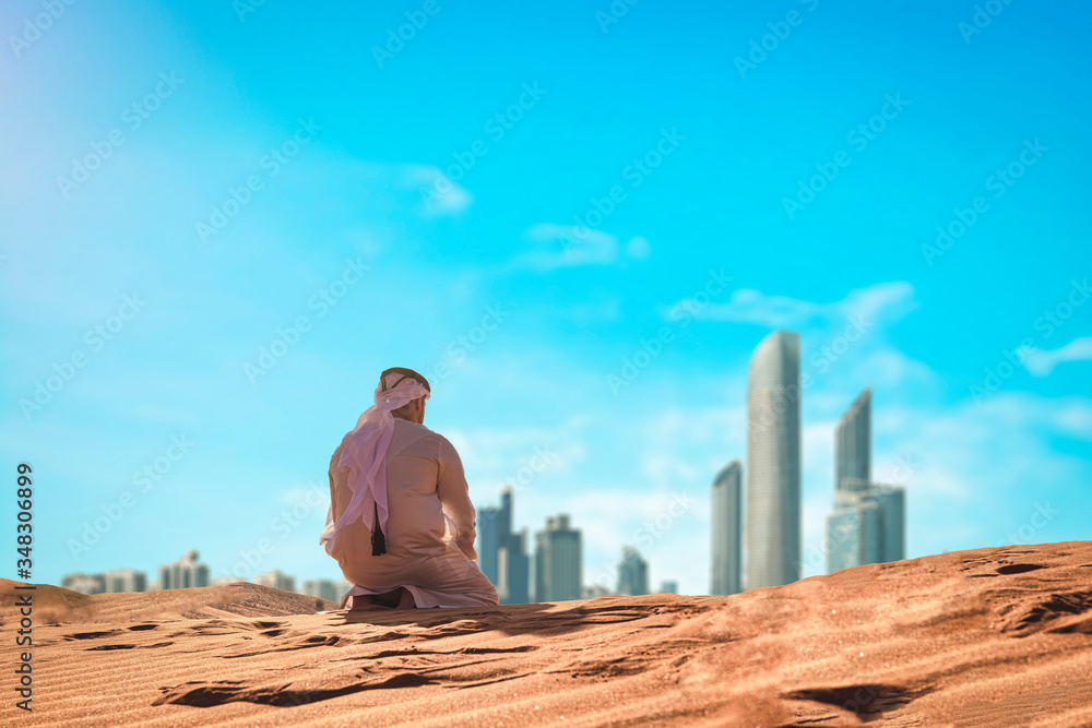 Arabic man with traditional emirates clothes sitting on kness in the ...
