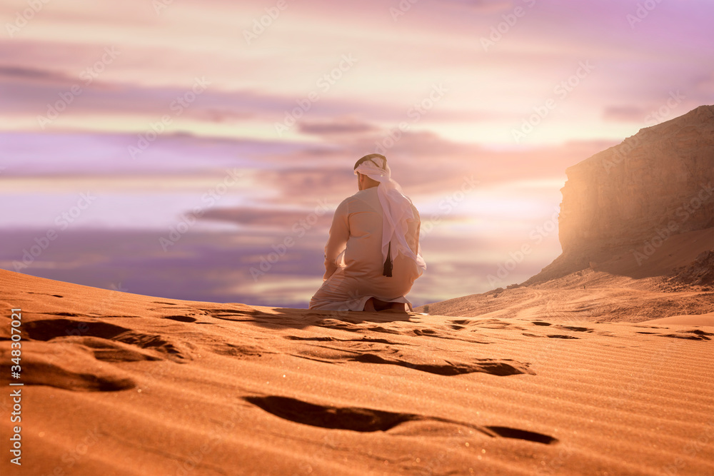Arabic man with traditional emirates clothes sitting on kness in the ...