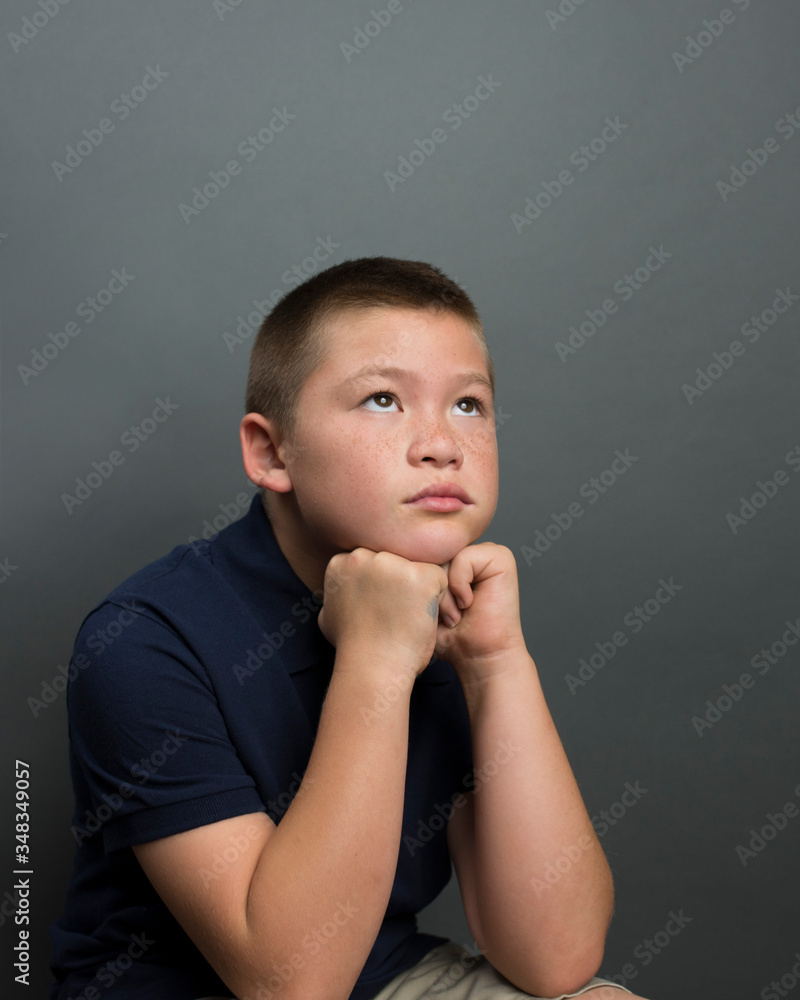 Foto de Preteen boy leaning on knuckles of both hands and looking up in ...