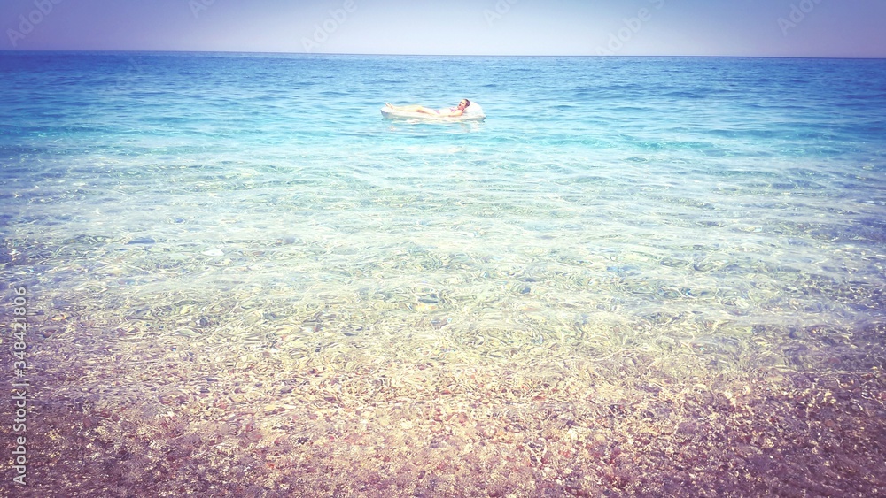 Woman Lying On Pool Raft While Floating In Sea Stock Photo | Adobe Stock