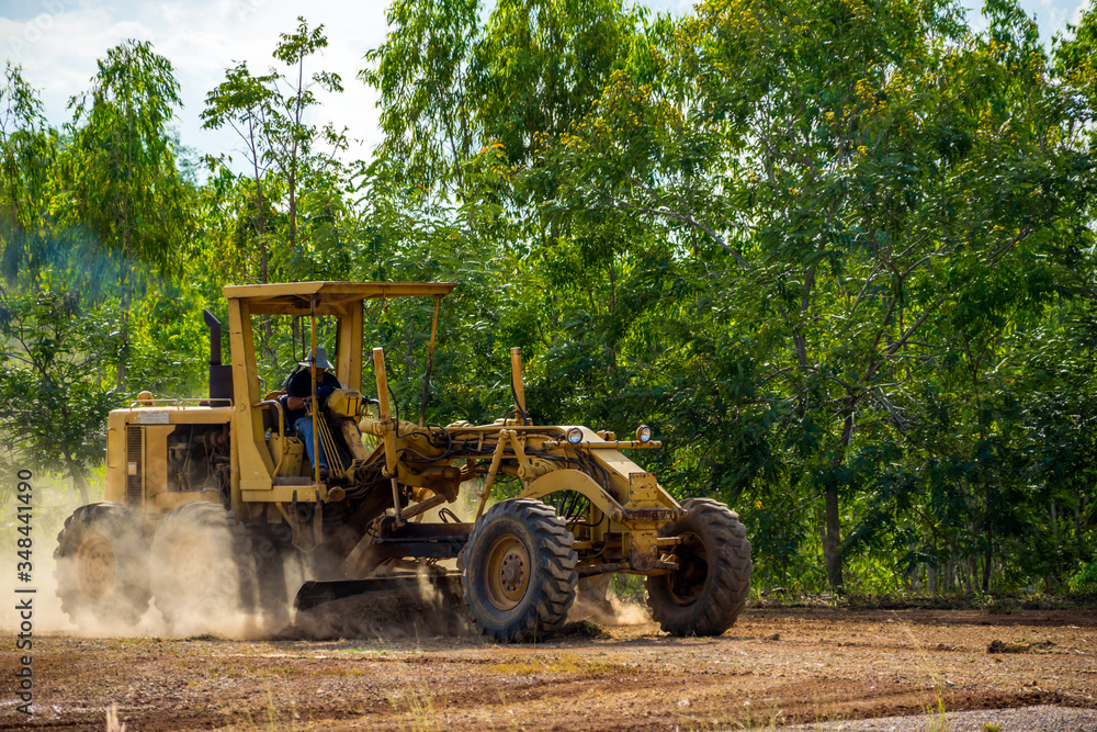 Motor grader clearing and leveling construction site surface with ...