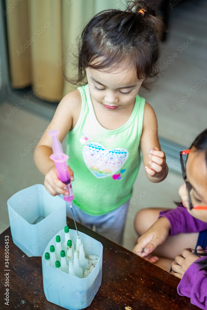Child injecting organic fertilizer into small containers to be placed ...