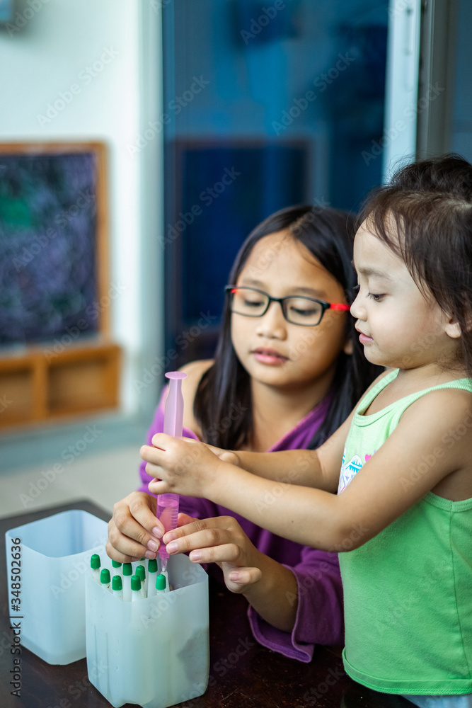 Child injecting organic fertilizer into small containers to be placed ...