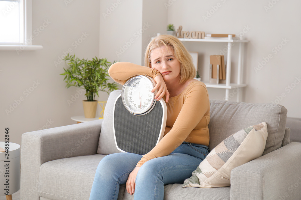 Sad overweight woman with scales at home Stock Photo | Adobe Stock