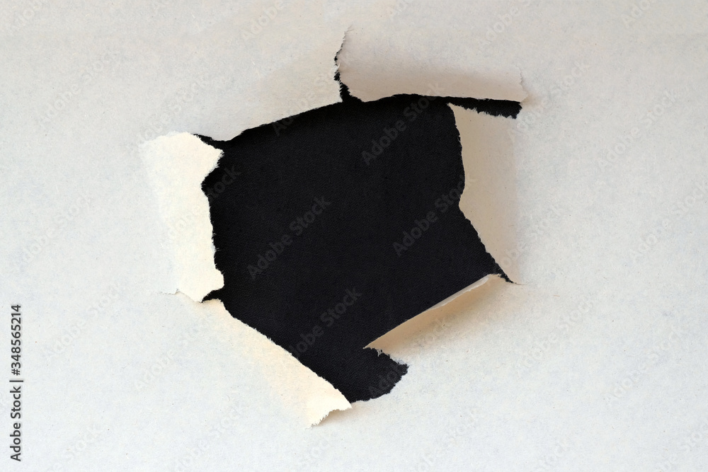 hole in white paper with black paper backing. Curled Tear on a black ...