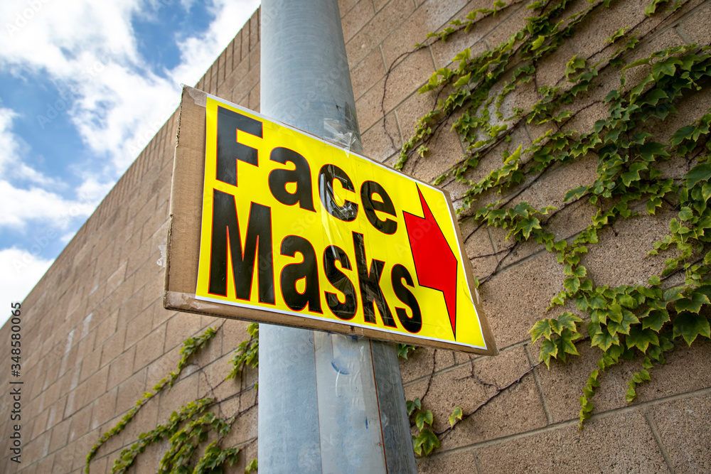 Sign on light pole with red arrow pointing right advertising FACE MASK ...