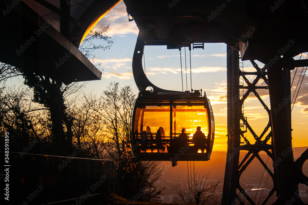 Ski lift silhouette with people inside and beautiful orange sunset at ...