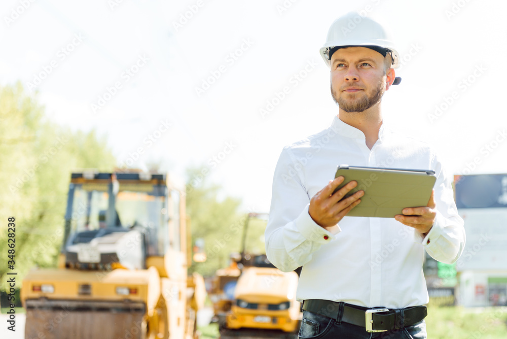 engineer near road machinery. The concept of building a new asphalt ...