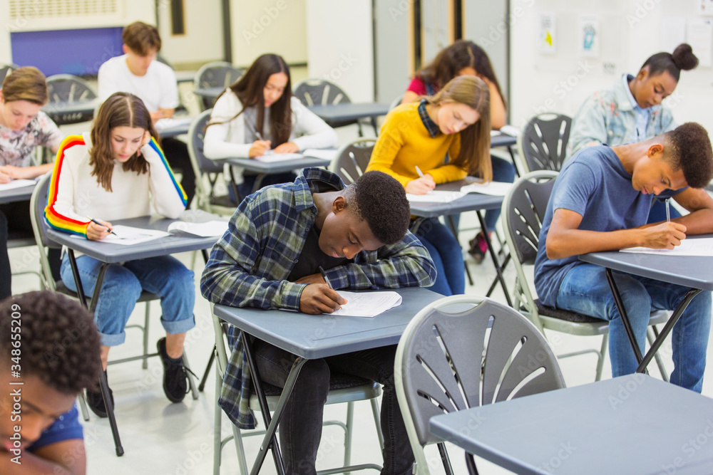 Focused high school students taking exam at desks in classroom Stock ...
