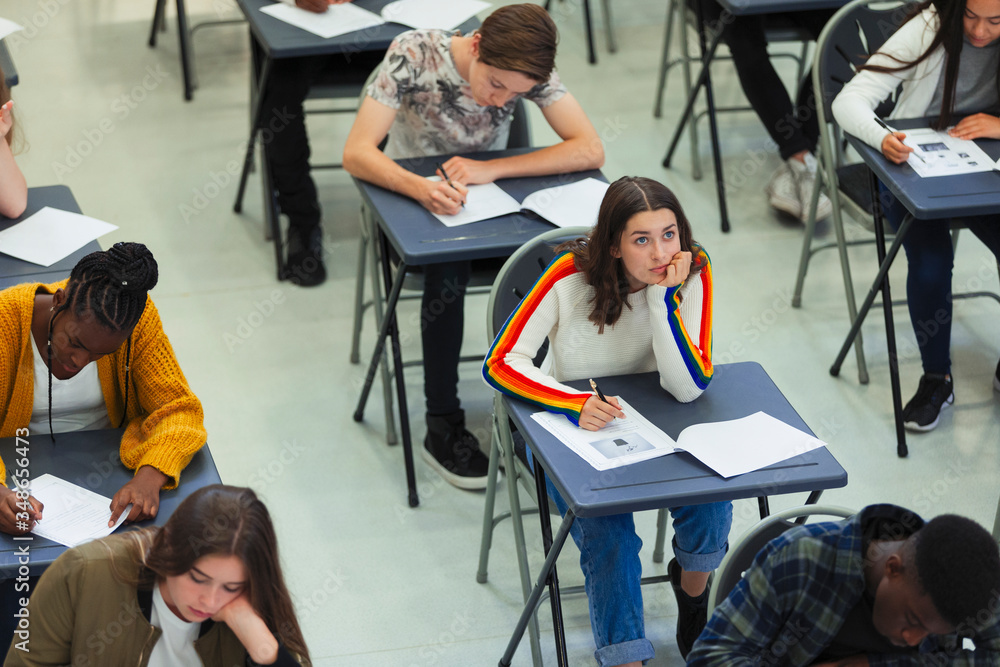 Thoughtful high school girl taking exam at desk in classroom Stock ...