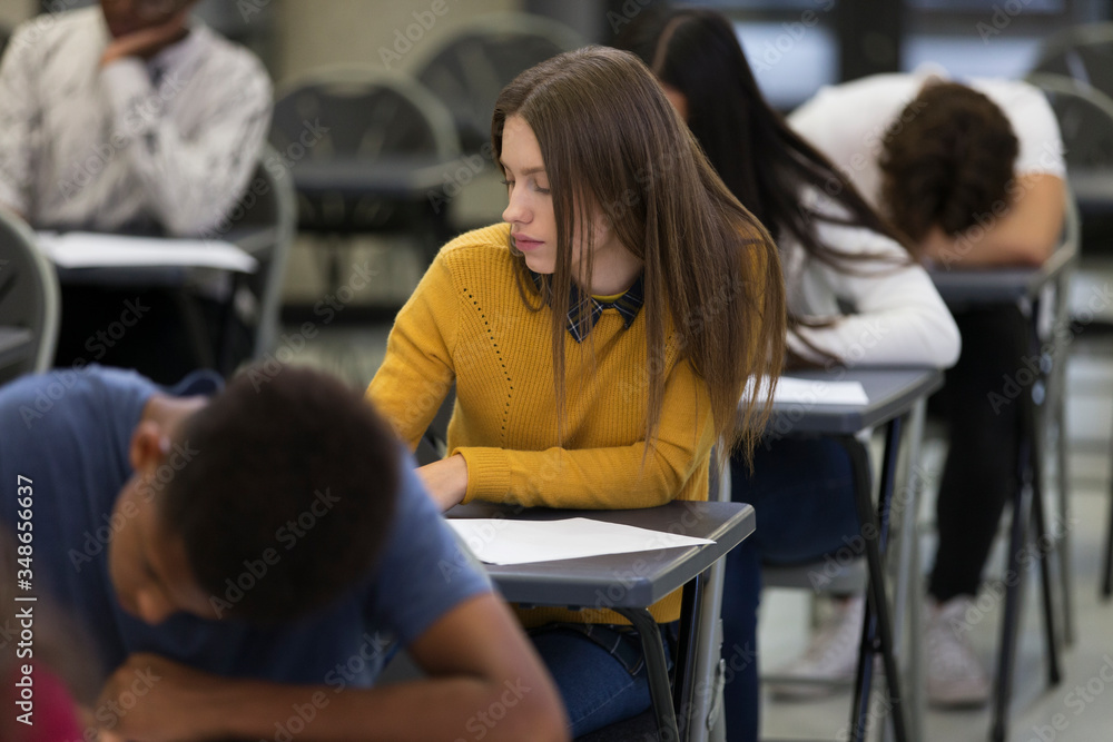 Foto de Focused high school girl student taking exam at desk in ...