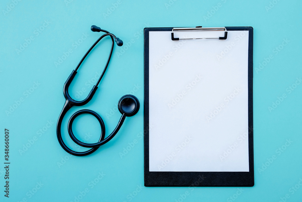 Black modern stethoscope and blank medical form on light blue ...