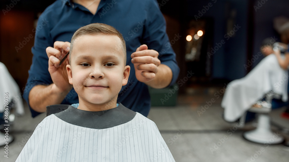 Perfect haircut. Portrait of little cute boy sitting in a barbershop ...