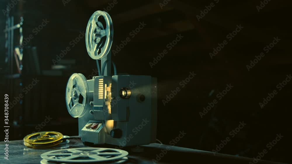 Vintage movie projector is working, showing old movie, film reels are ...