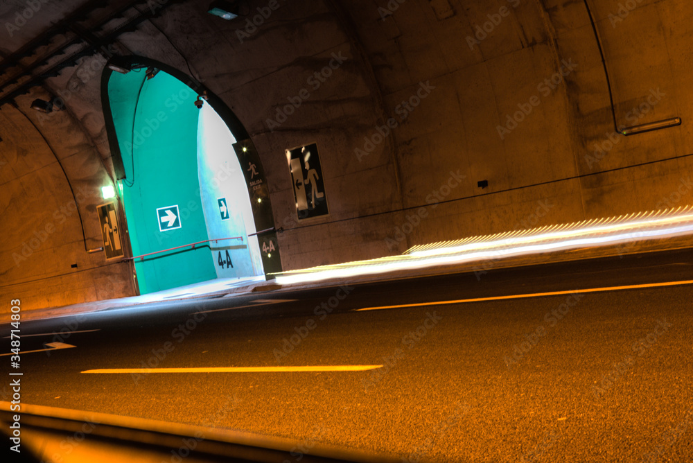 Emergency exit inside tunnel with car lights passing by. Long exposure ...
