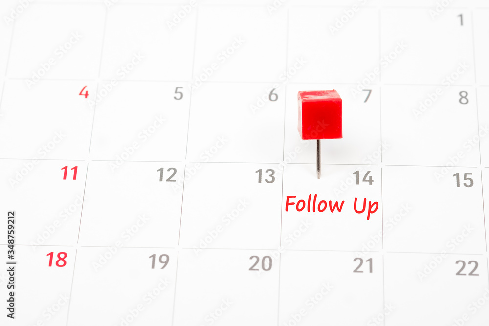 Follow Up written on a calendar with a red push pin to remind you and ...