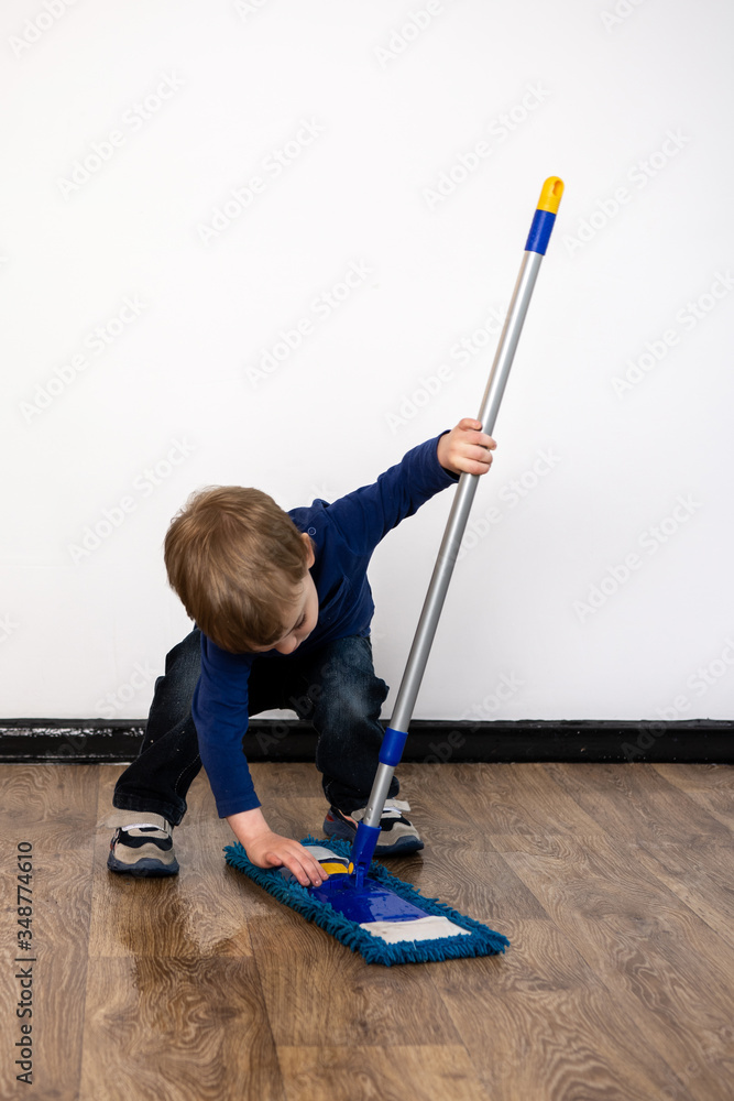 little boy mops the floor in an apartment. general cleaning of the ...