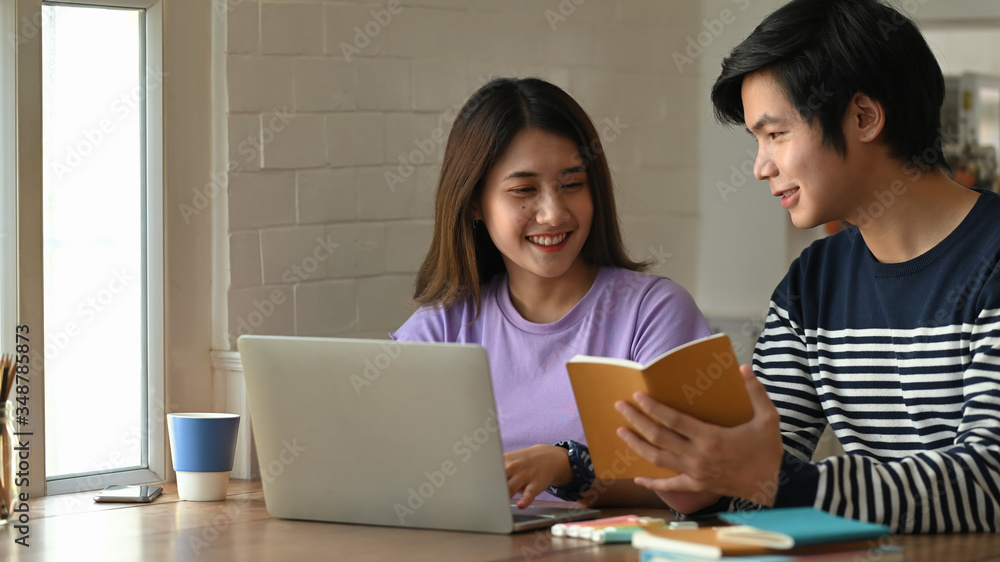 Couple tutoring their lesson while sitting together in front of computer laptop at the wooden ...