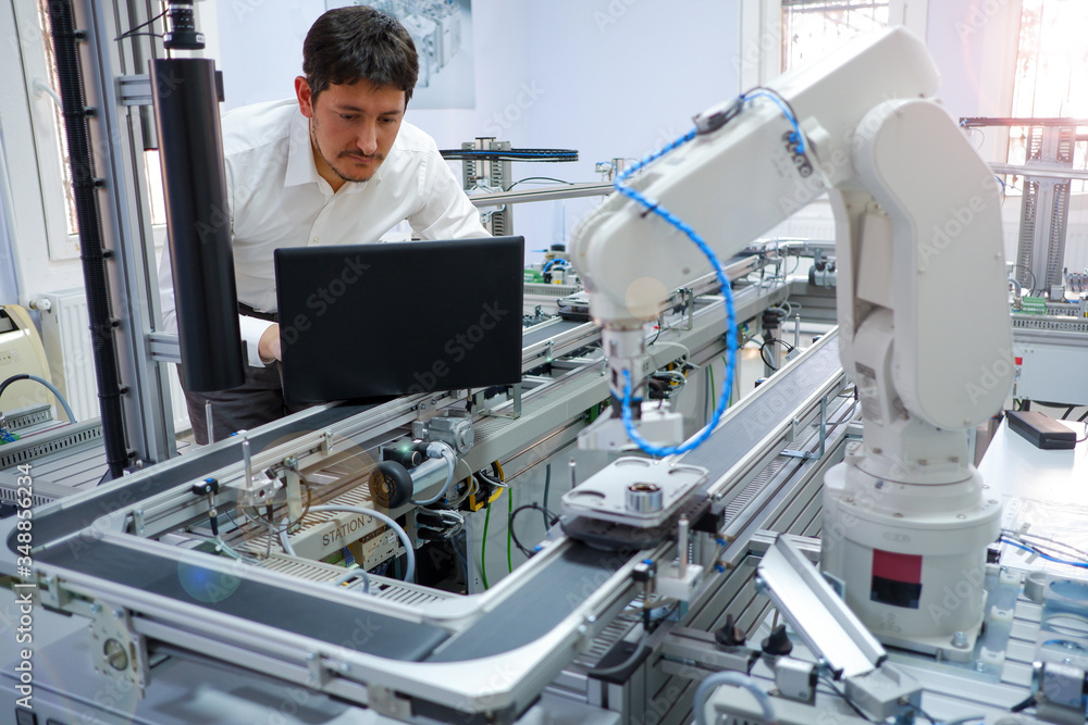 Close-up robot arm. Engineer is working on laptop to programming smart ...