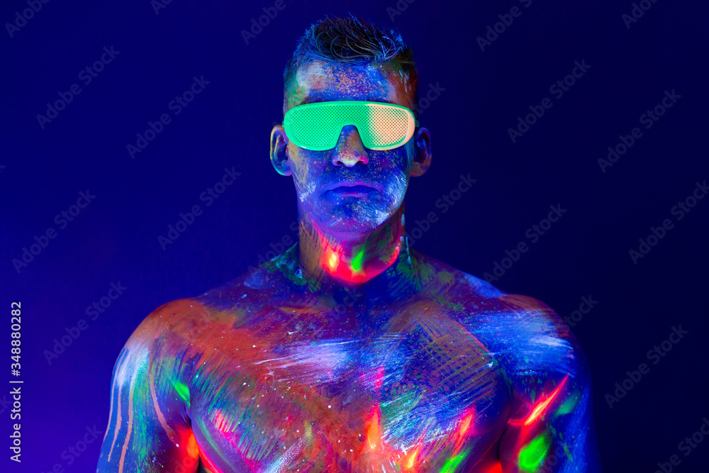 .Portrait of a pumped-up man at a disco. Fluorescent paint on face in ...