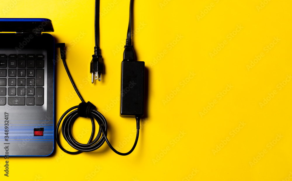 Notebook and laptop charger over yellow background. Adventure, travel ...
