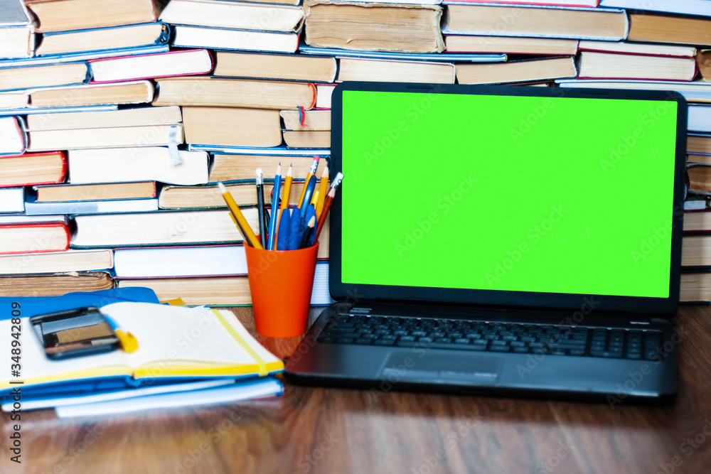 Textbook, notebook, green screen laptope and stack of books. Work from ...