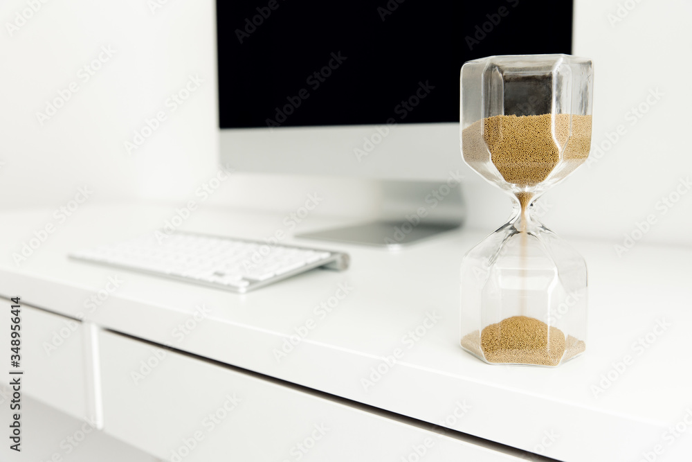 Working time concept. Hourglass is on desktop, against background of ...