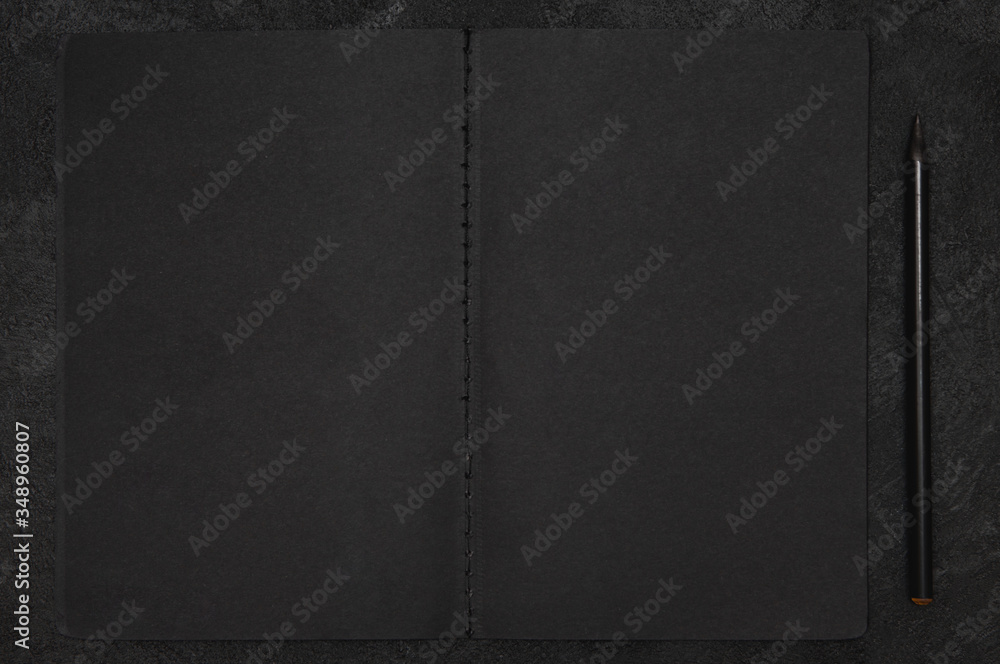 Top view of notepad with black paper sheets and black pencil on ...