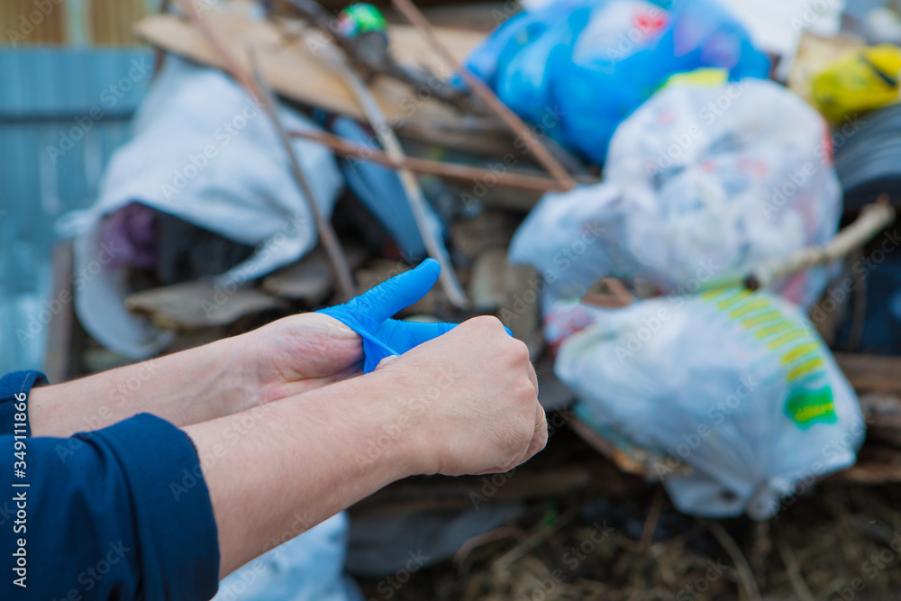 a man wears rubber gloves for garbage collection. a lot of garbage in ...